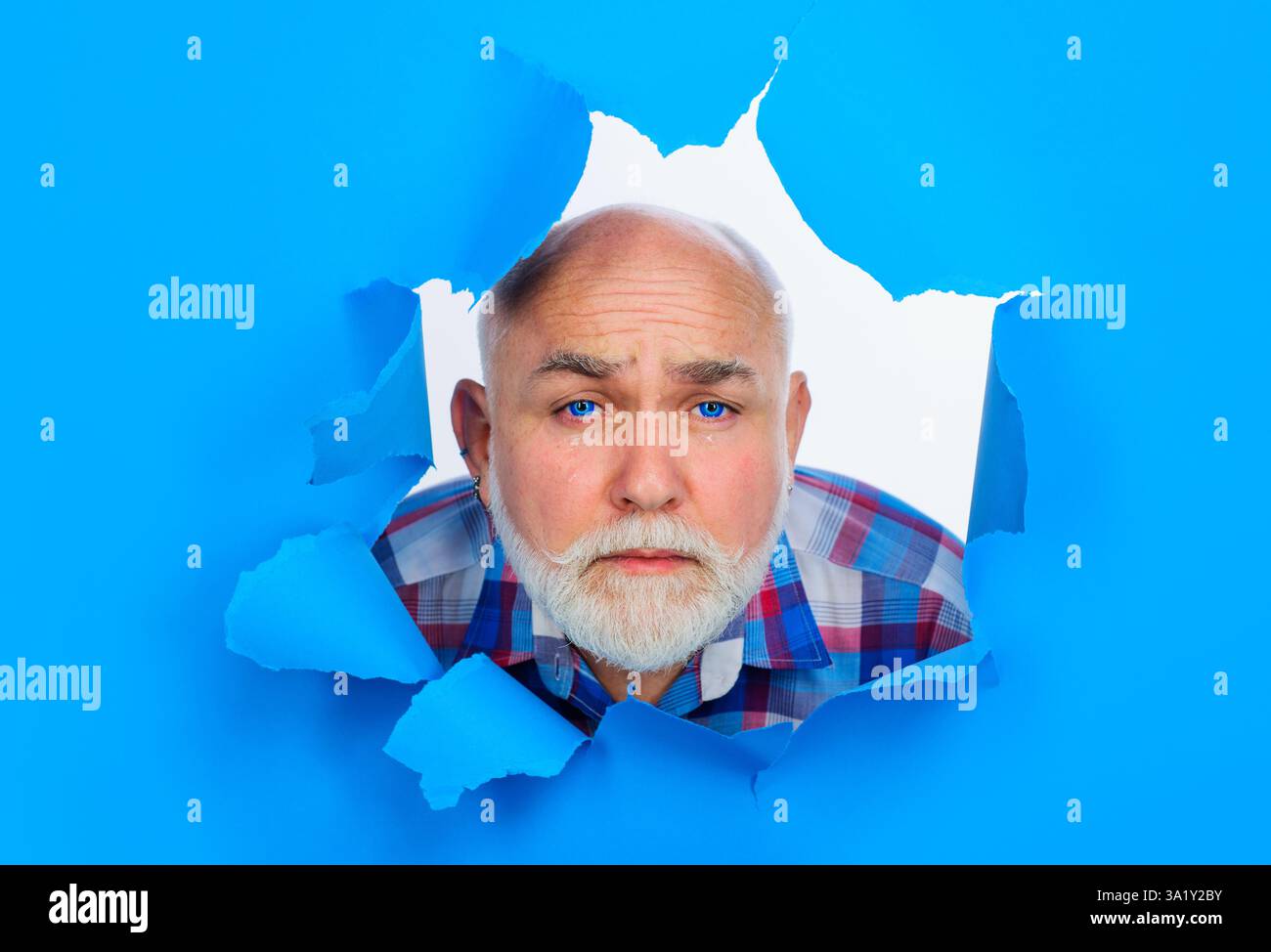 Bearded man with blue color lenses in eyes looking through hole in ...