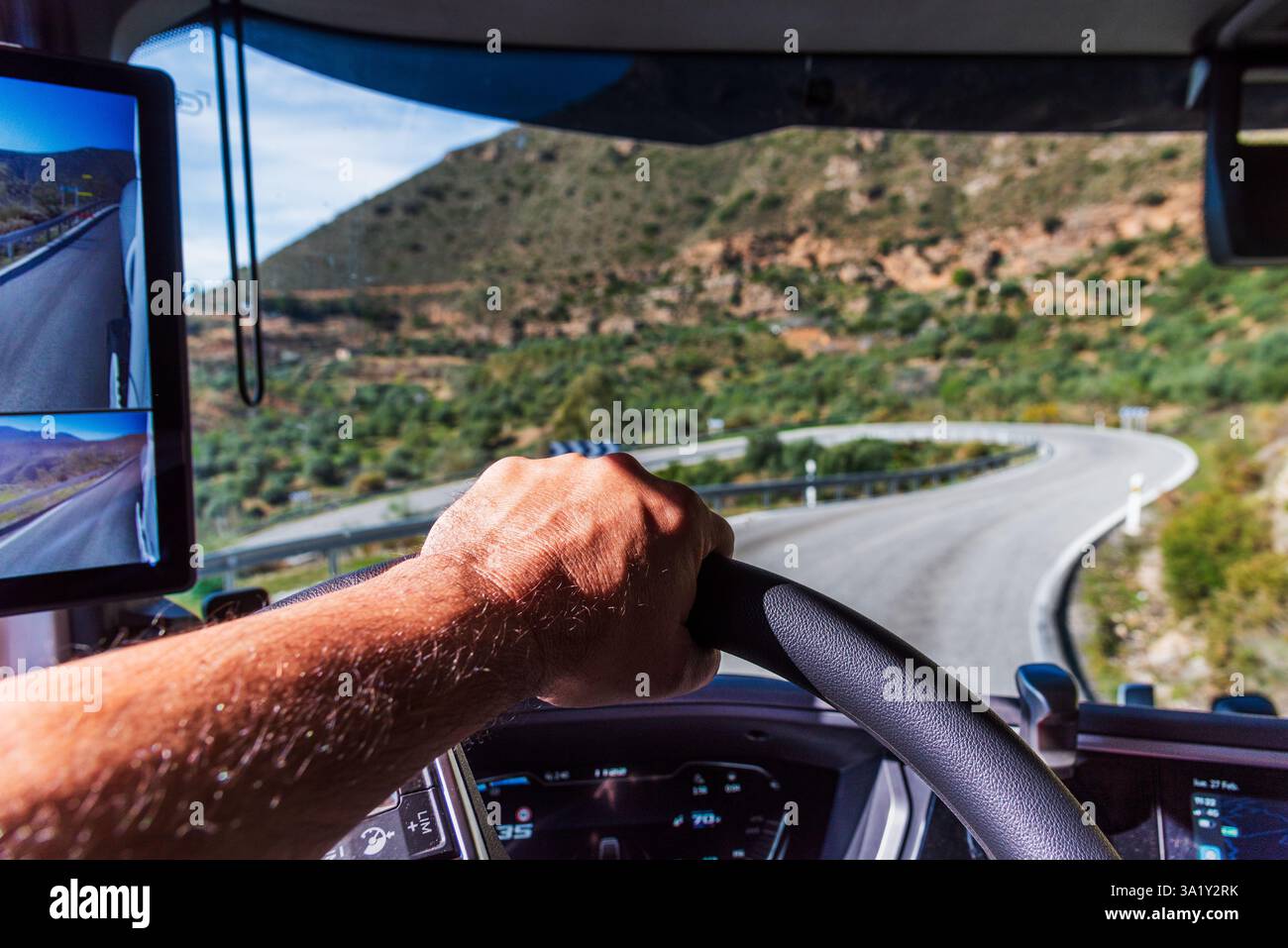 Driver's hand firmly gripping the steering wheel on a mountain descent ...