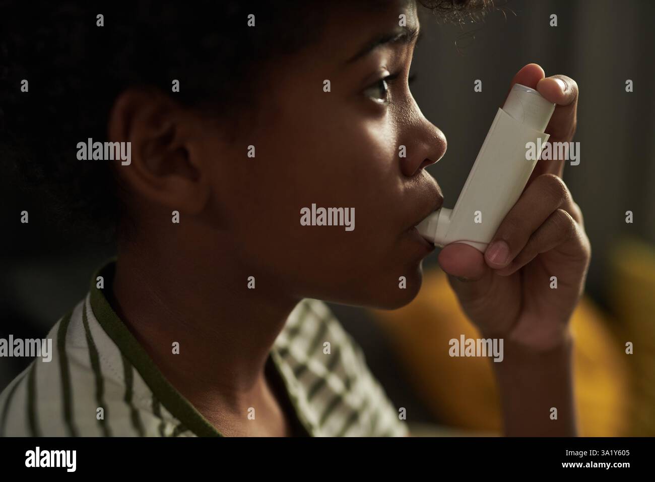 Close-up of face of youthful boy with asthma attack pumping inhaler in ...
