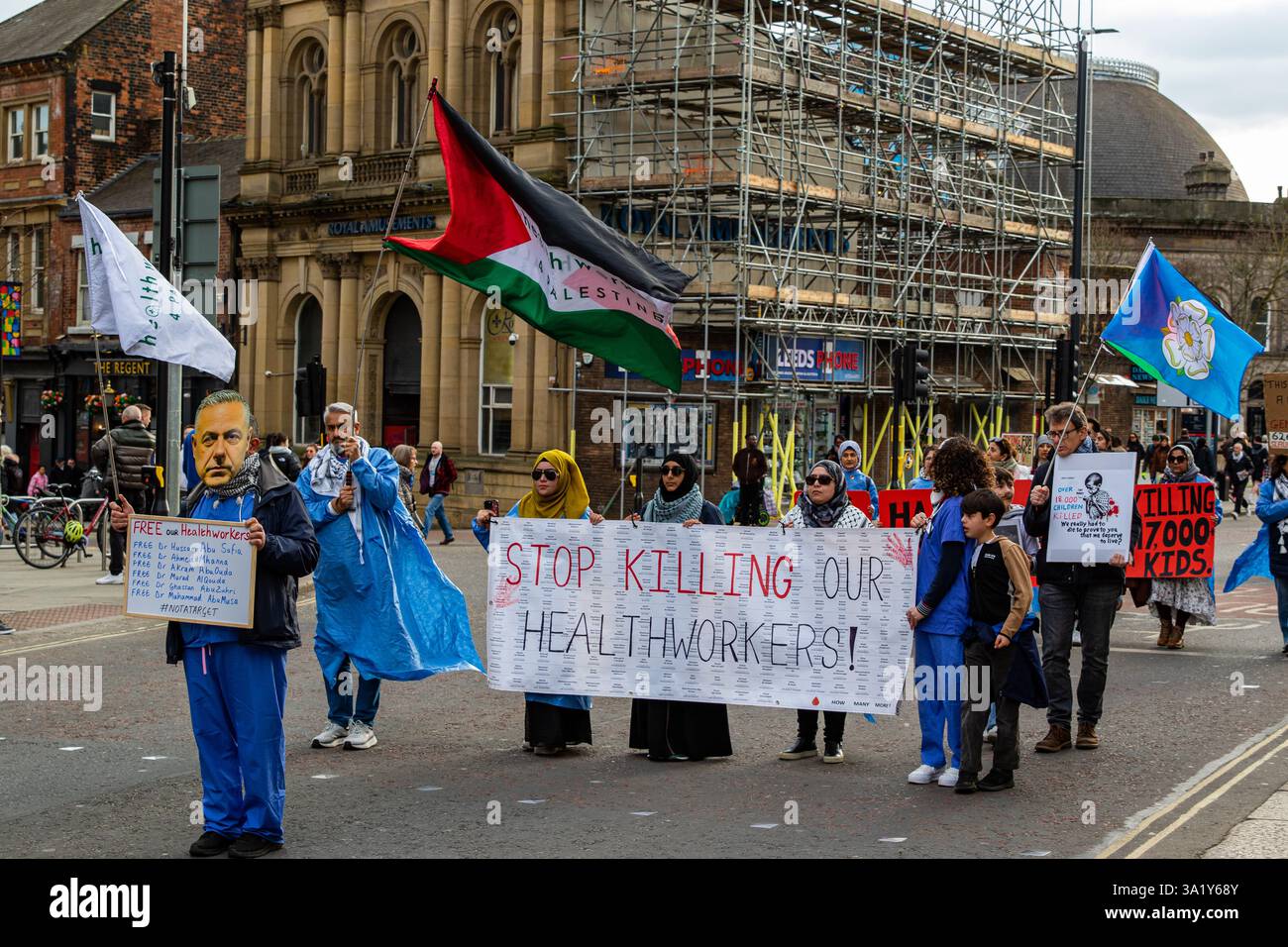 Protesters march on a city street holding signs and flags, expressing ...