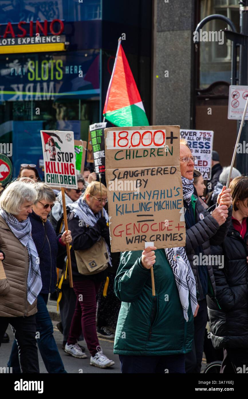 A group of people are marching in protest, holding signs advocating for ...