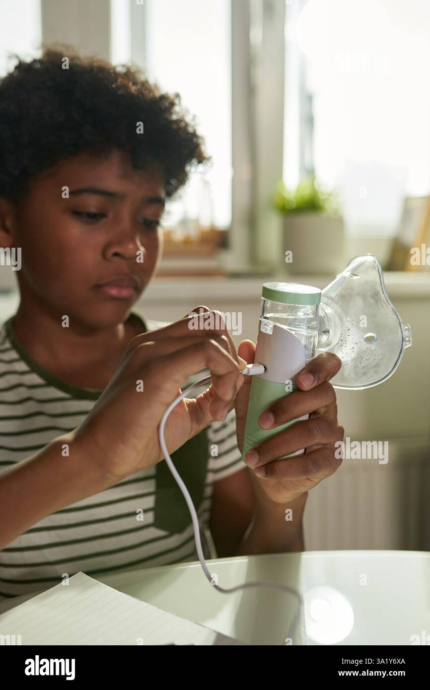Cute youthful boy with asthma switching inhaler with mask while ...