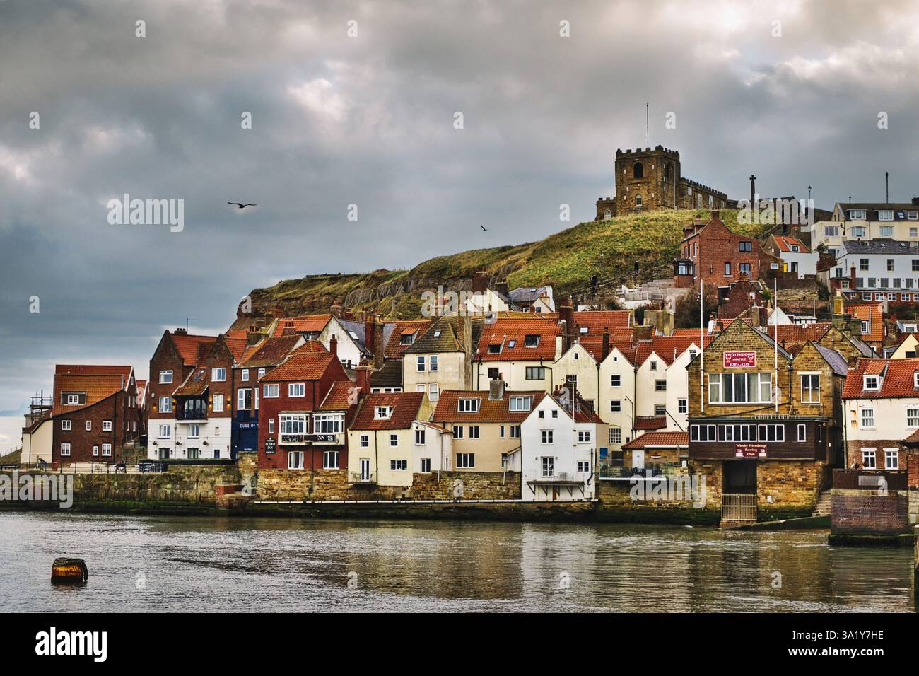 Coastal townscape featuring buildings with red roofs, a hilltop church ...