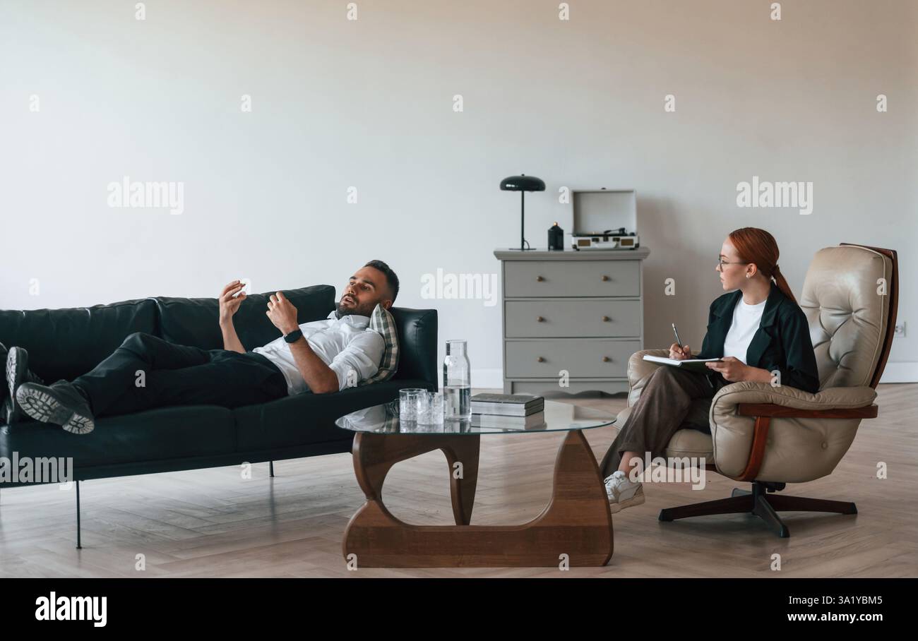 Man is lying down on the sofa, session with woman psychologist Stock ...