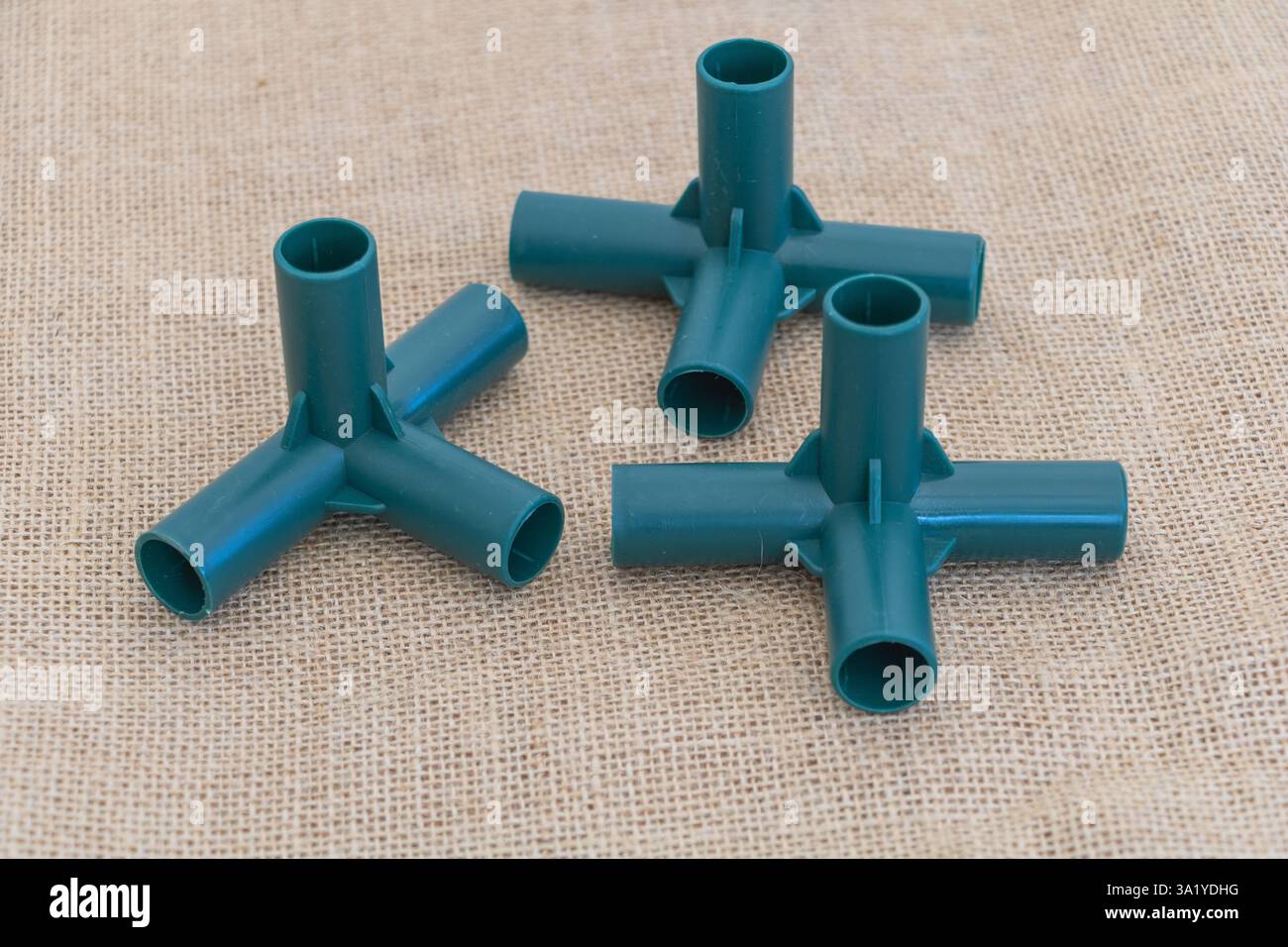 Plastic pipe connection pieces, in a dark green color, on a burlap ...