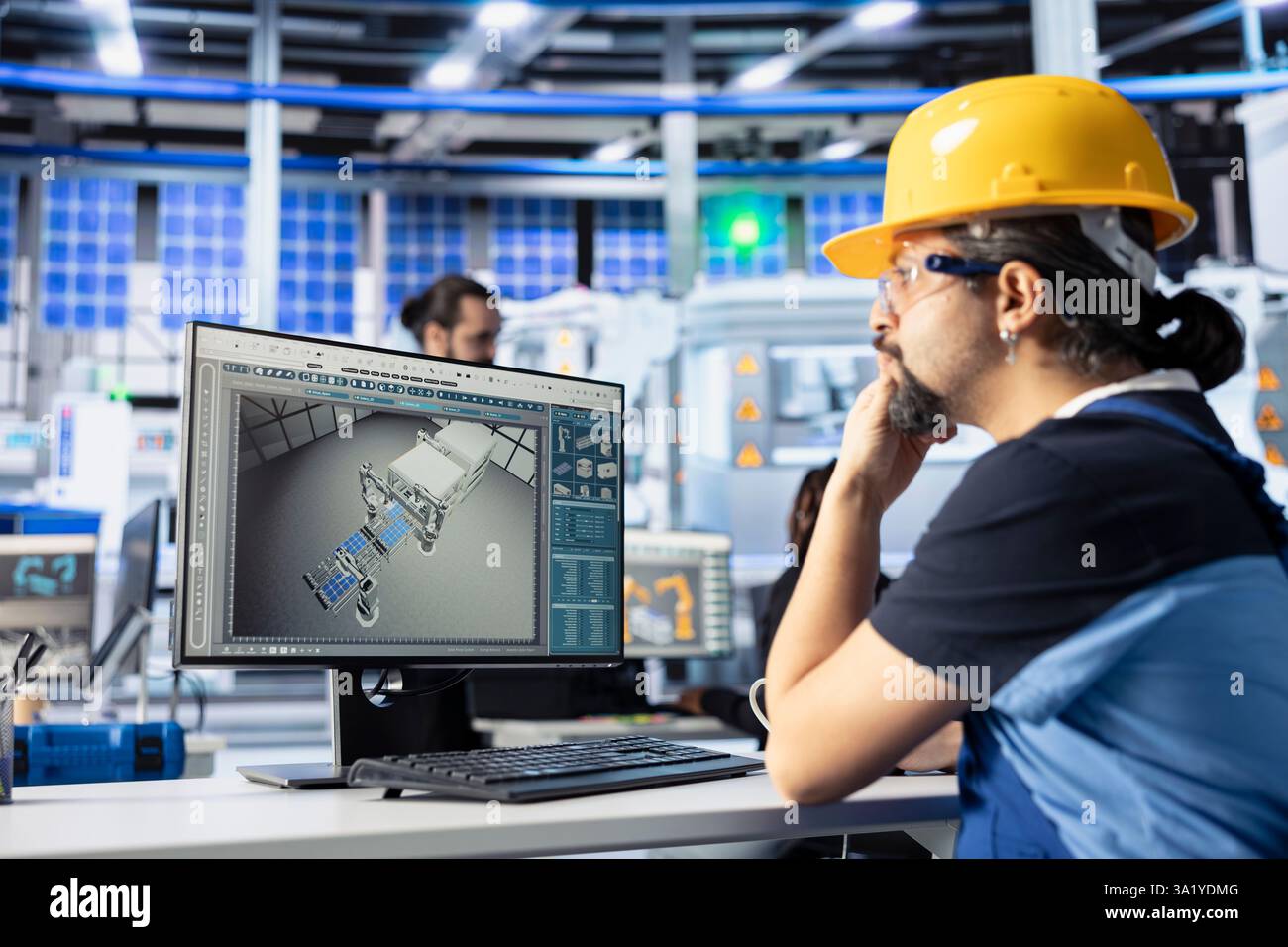 Technical engineer using computer to monitor solar panel assembly line ...