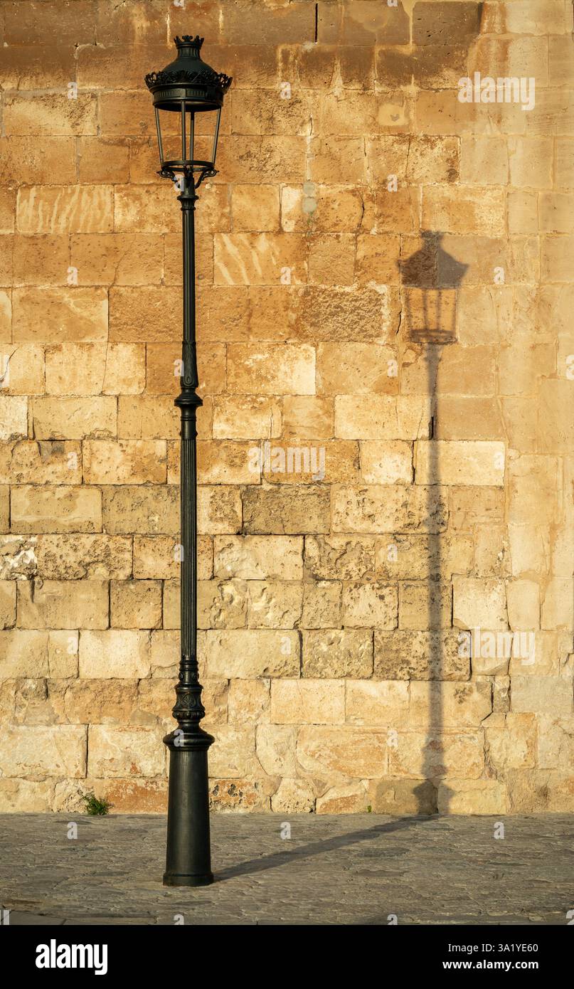 Vertical image of a vintage street lamp casting a long shadow on an old ...