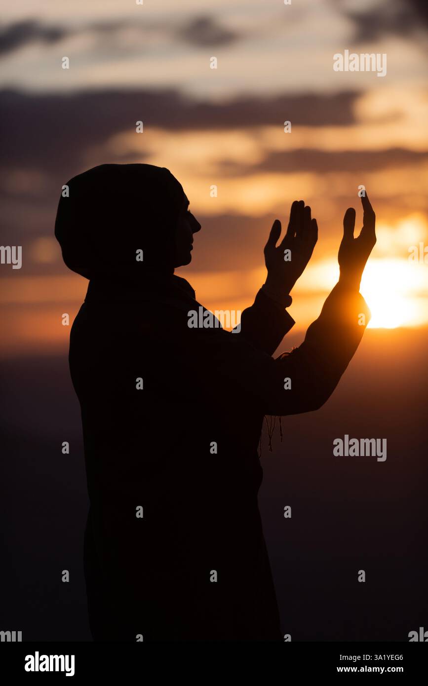 Muslim woman prayer praying with hands up open doing dua at sunset ...
