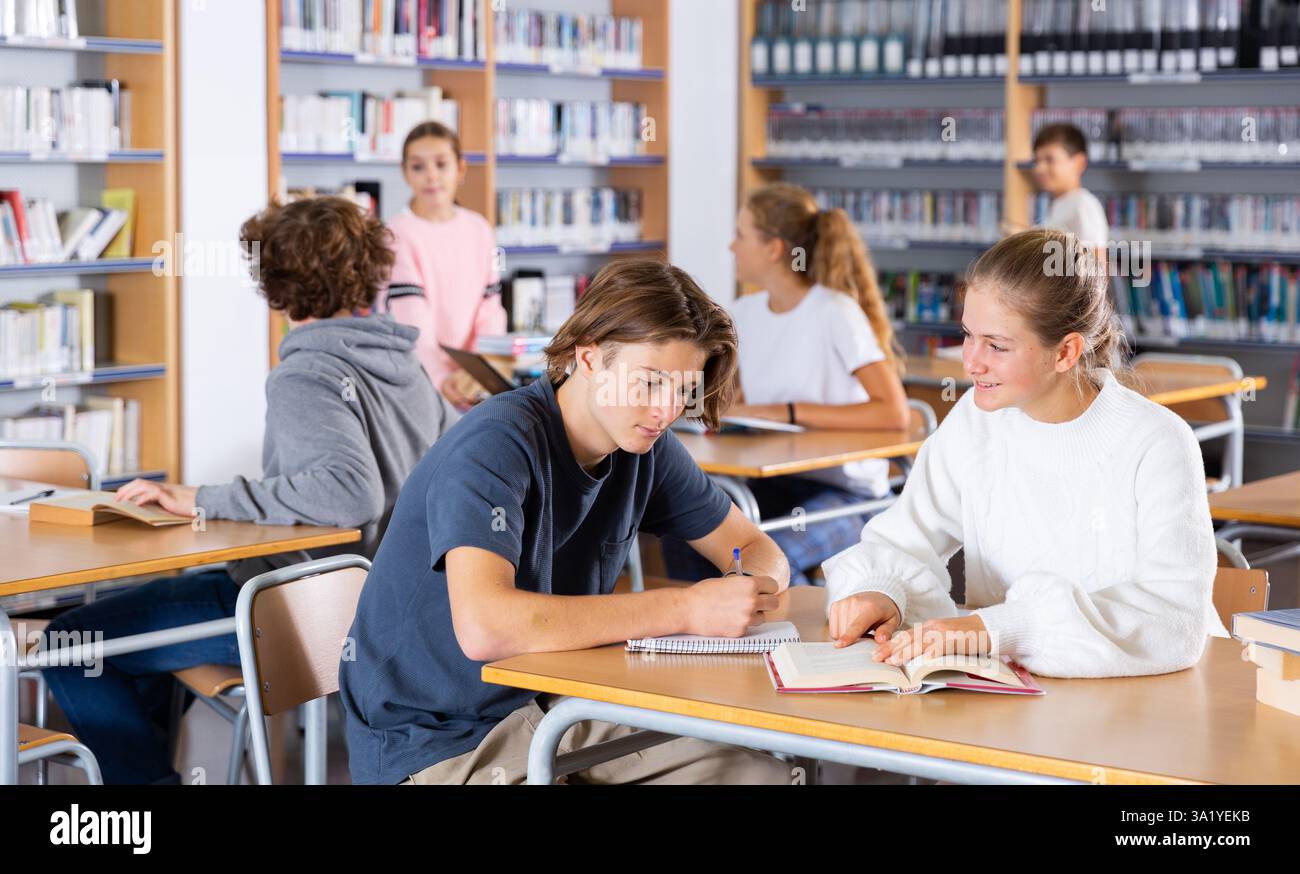 Cute tween girl and intelligent boy studying together in library ...