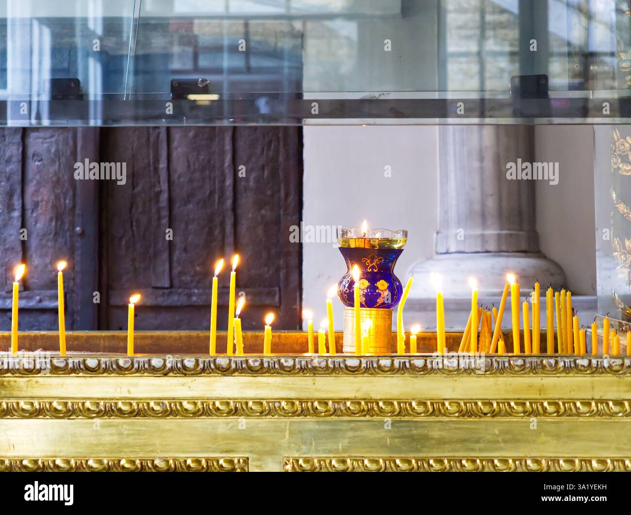 Multiple yellow candles burning on a decorative golden altar with a ...