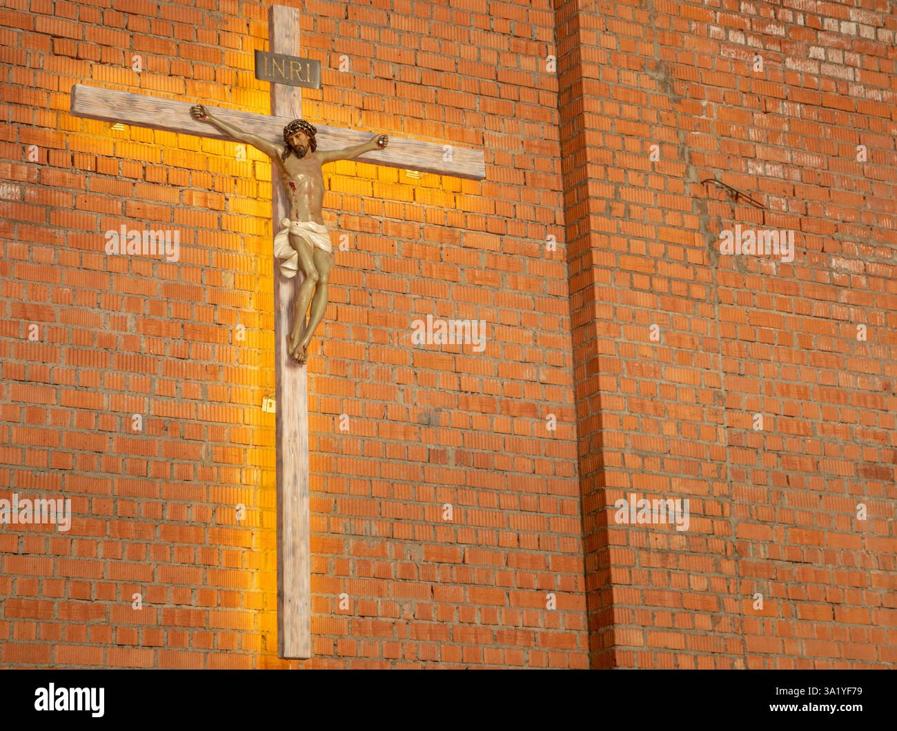 Jesus on a crucifix in front of a stone brick wall Stock Photo - Alamy