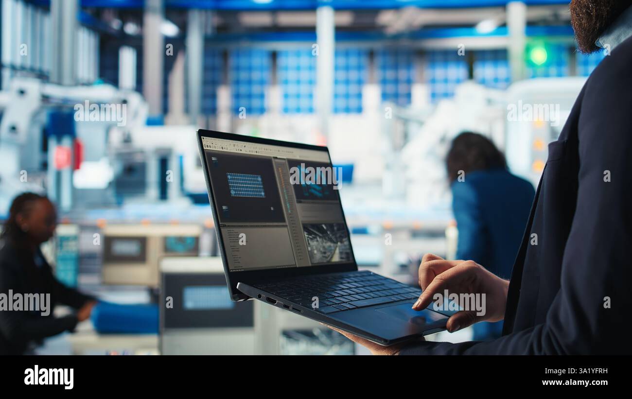 Photovoltaics factory worker analyzing data, reviewing system health metrics with laptop. Solar ...