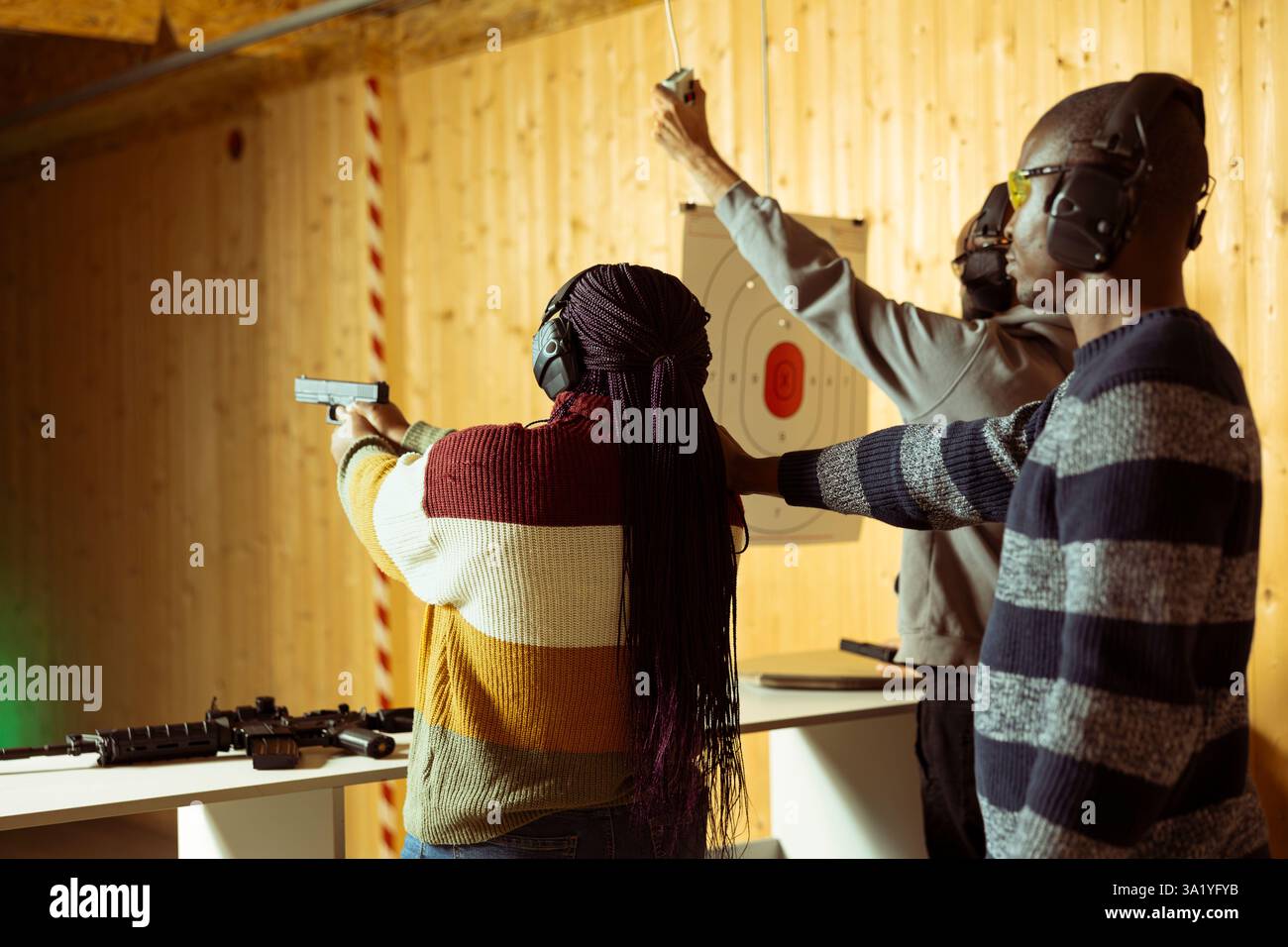 Shooting gallery staff member teaching student how to hold and handle ...