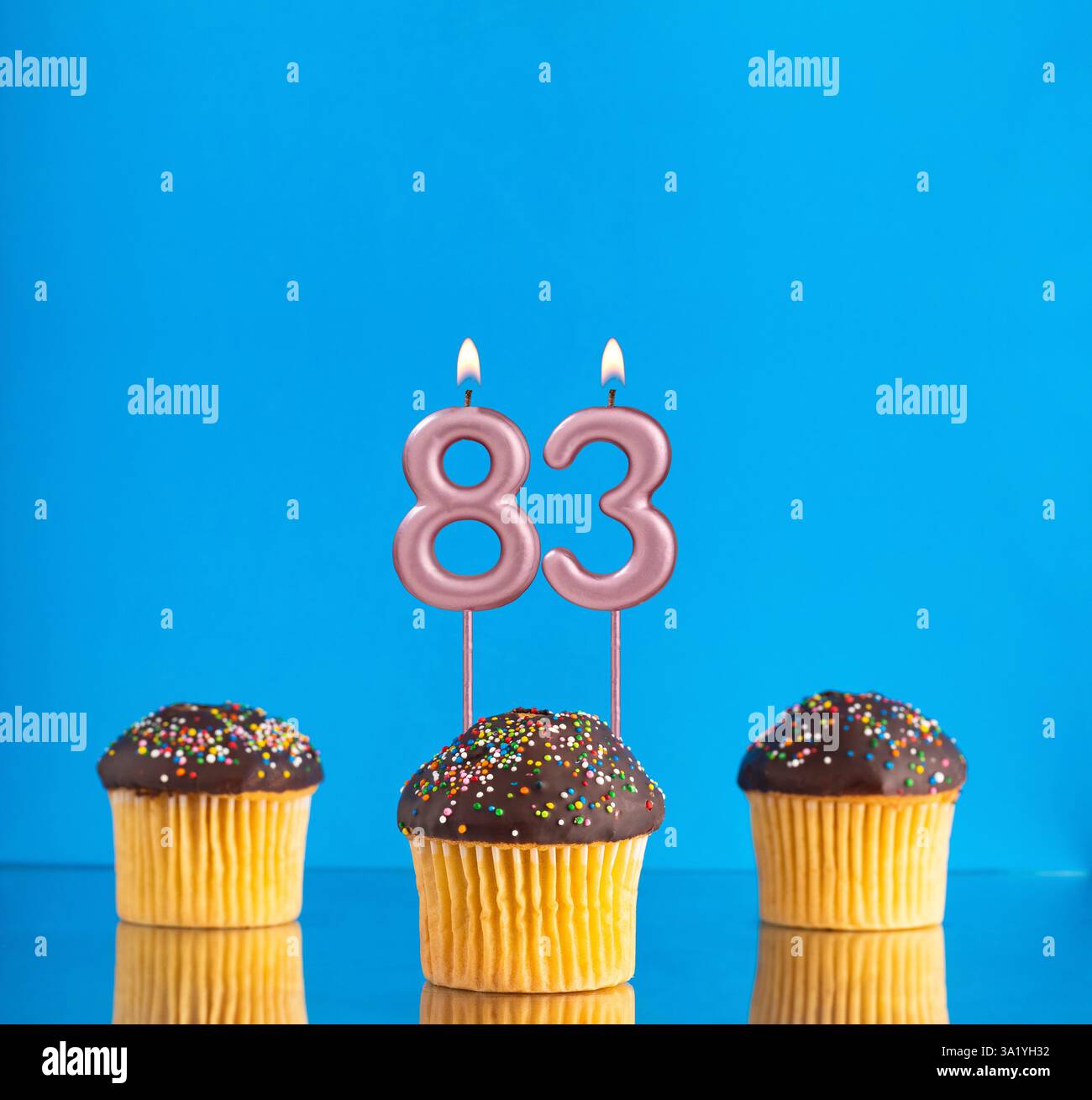 Three birthday cupcakes with number 83 candle - Blue background Stock ...