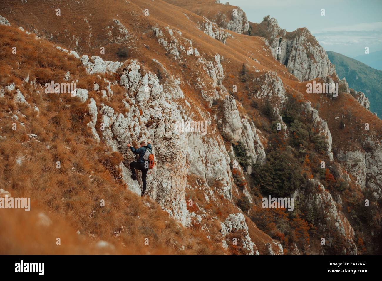 A male climber climbing up on the mountain rock cliff, adventure travel ...