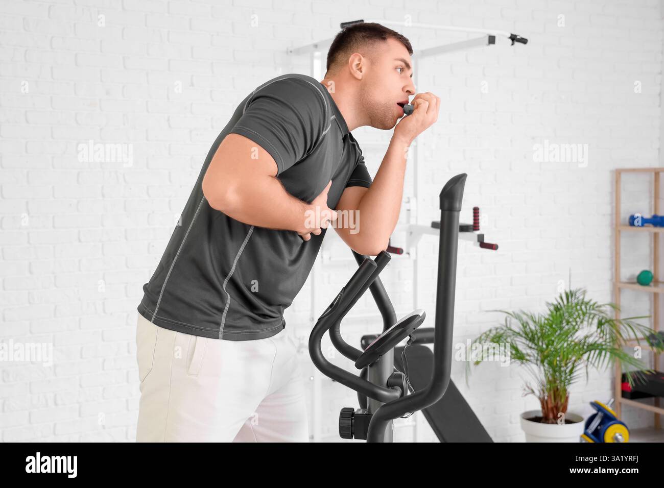 Sporty young man using inhaler on exercise bike in gym Stock Photo - Alamy