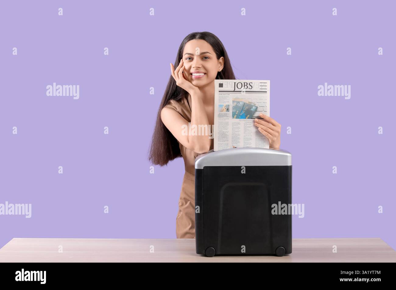 Happy young woman destroying newspaper using shredder on table against ...