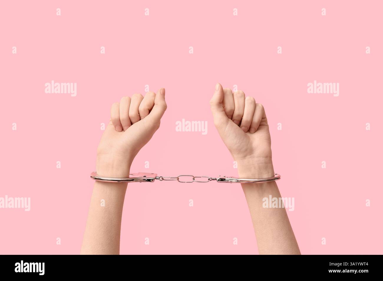 Female hands in handcuffs on pink background Stock Photo - Alamy