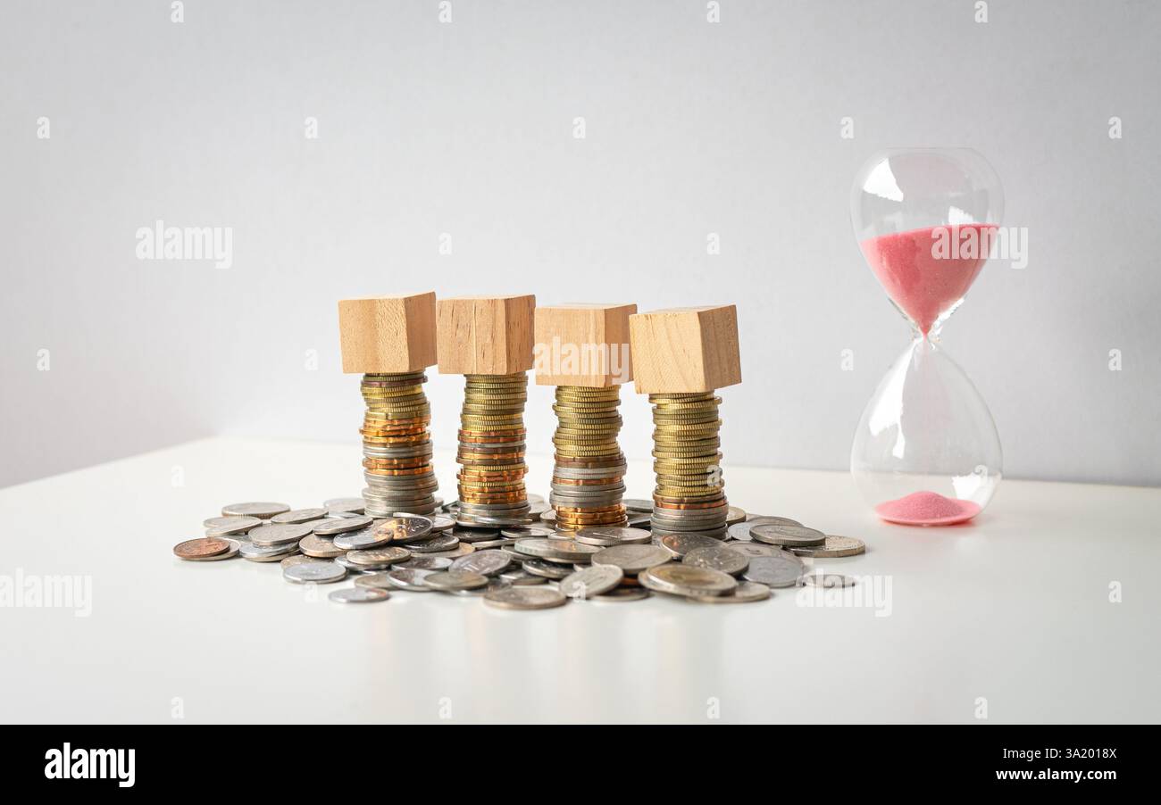 4 blank square blocks on top of stacked coins with sand timer. Copy ...