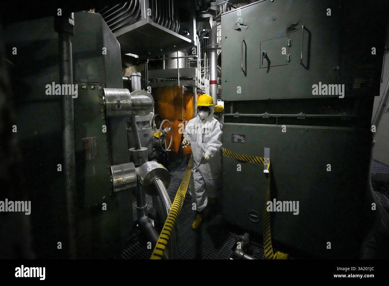 A worker in hazmat suit walks at the area under the Unit 5 reactor ...