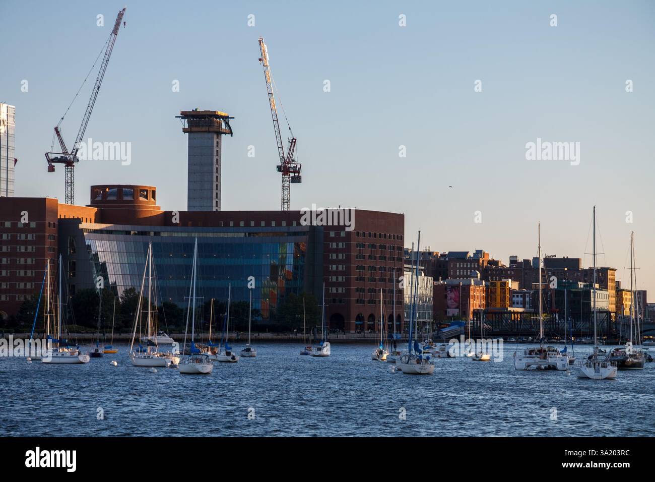 Sailboats at sunset, cranes and the buildings at the waterfront, Boston ...
