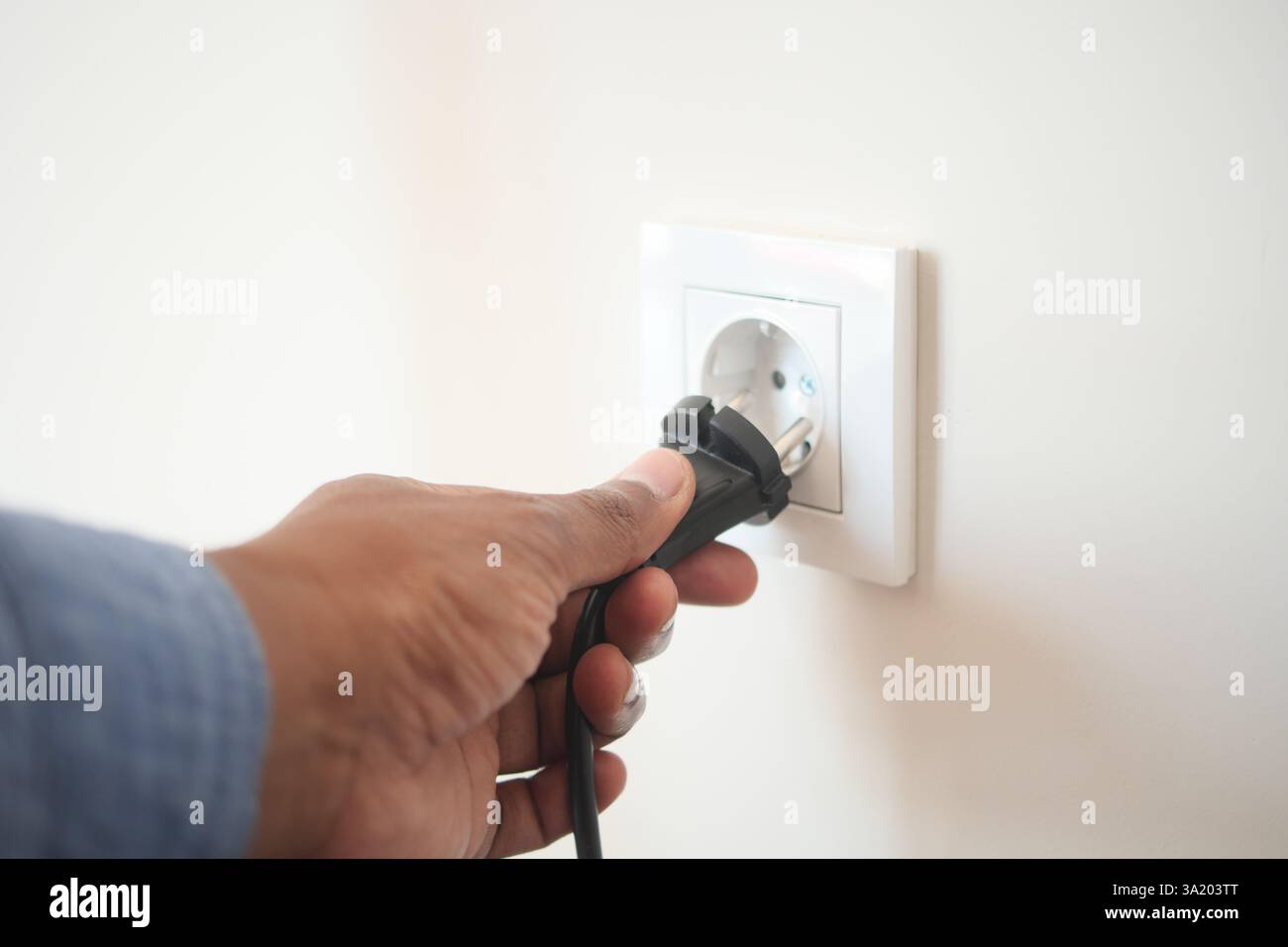 Hand inserting electrical plug into wall outlet at home Stock Photo - Alamy