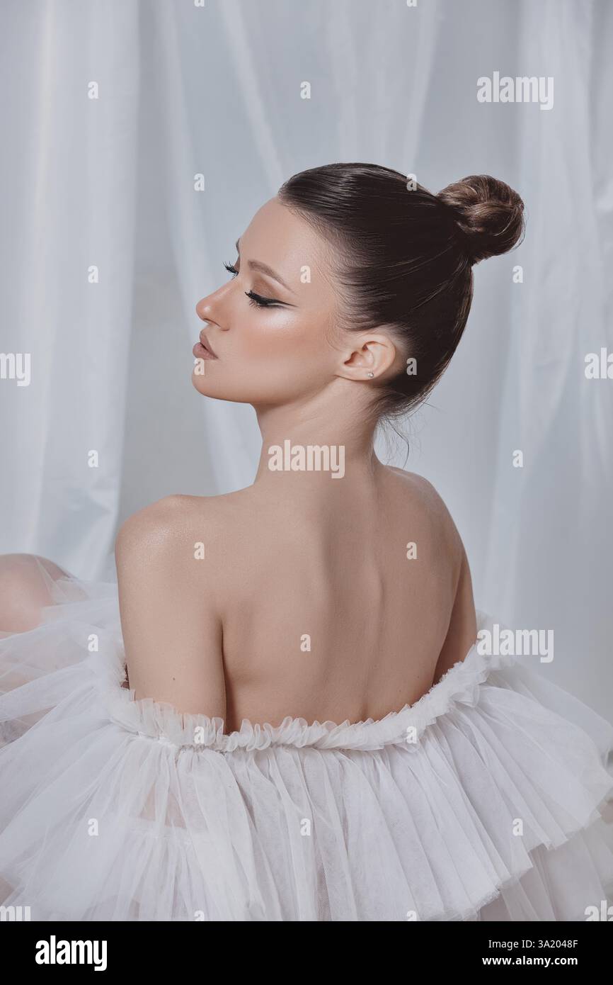 graceful woman showcases her profile with an updo hairstyle, wearing a ...