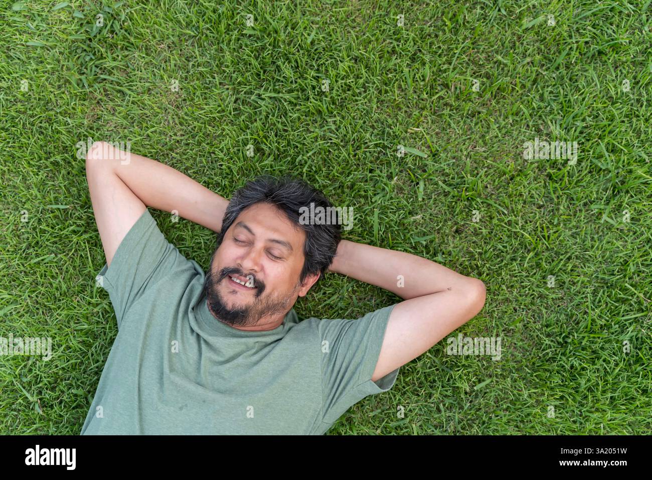 Handsome young man lying on the ground and relaxing in the park with ...