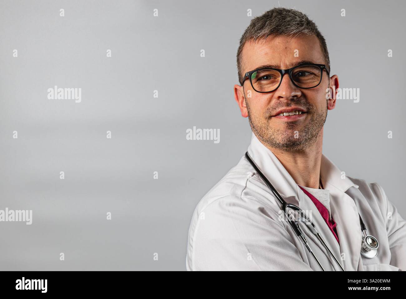 A healthcare professional wearing glasses and a white lab coat stands ...