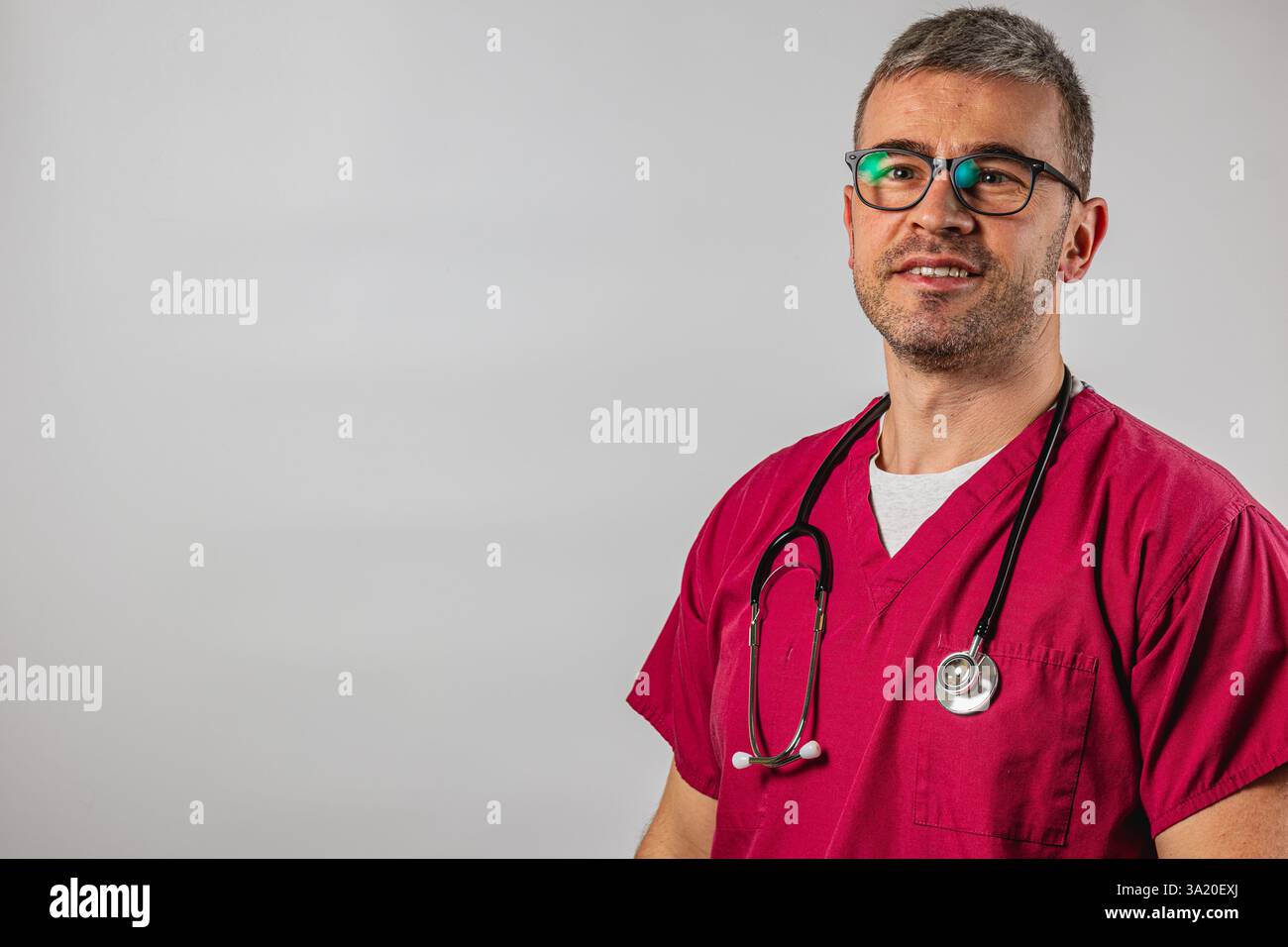 A male healthcare professional stands confidently, wearing red scrubs ...