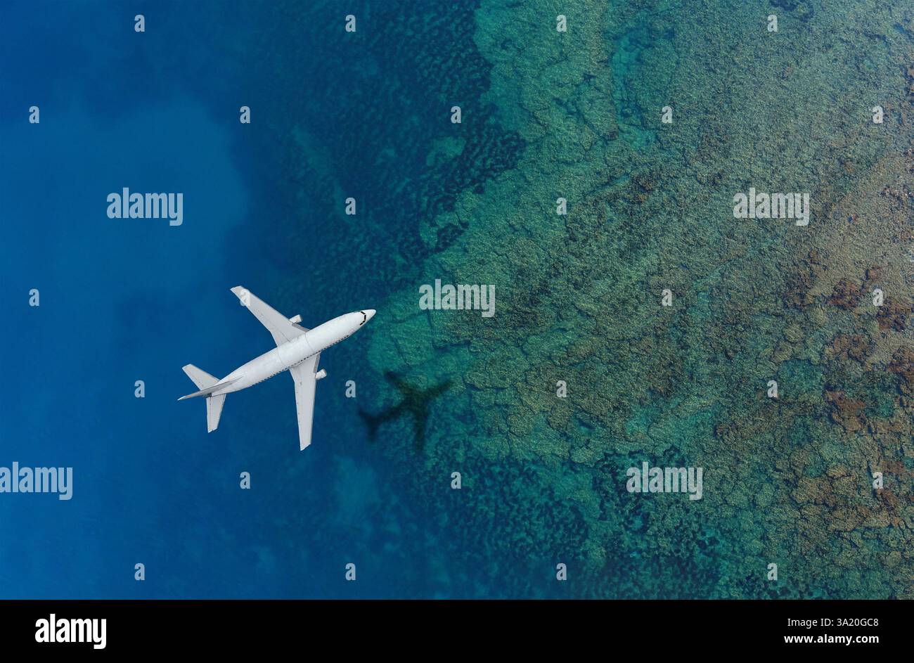 Airplane flying over clear blue ocean with reef visible below Stock ...