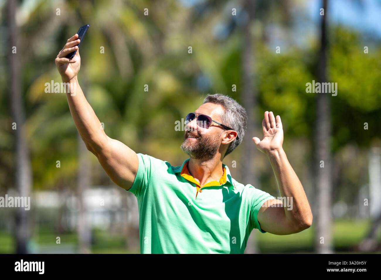 Tourist takes a selfie near palm tree. Man traveler captures a selfie ...