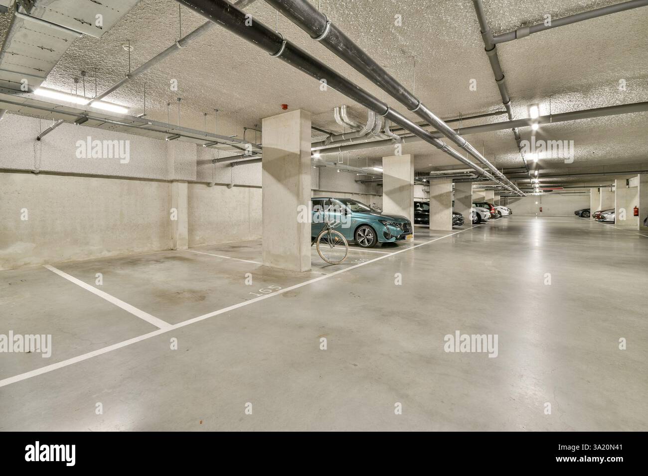 Spacious and well-lit underground parking garage featuring concrete ...