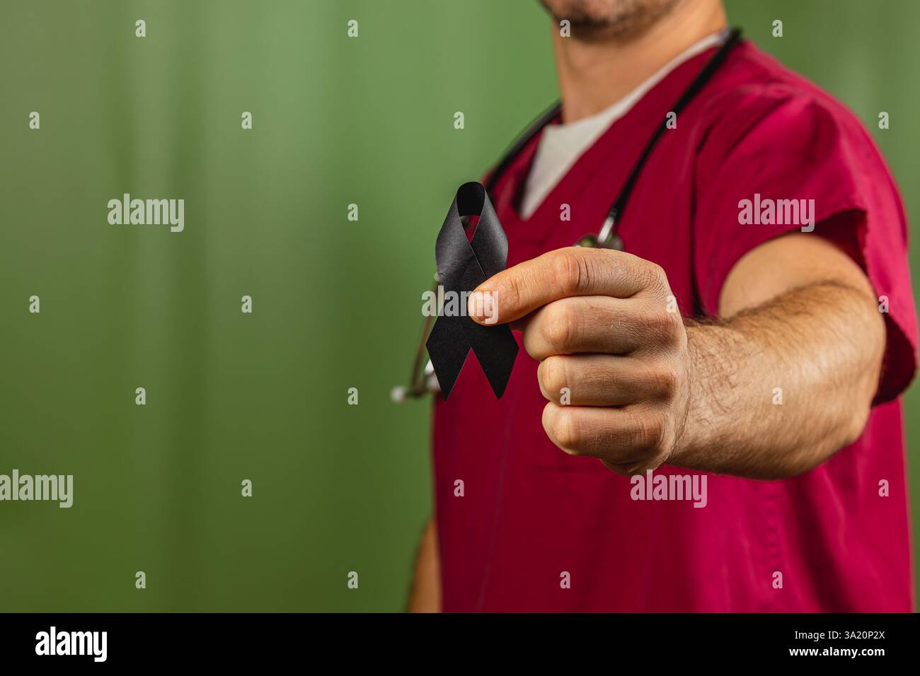 A healthcare worker in scrubs displays a black ribbon, symbolizing ...