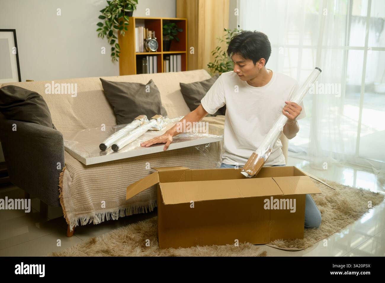 Young man unpacking parts of a new table from cardboard box preparing ...