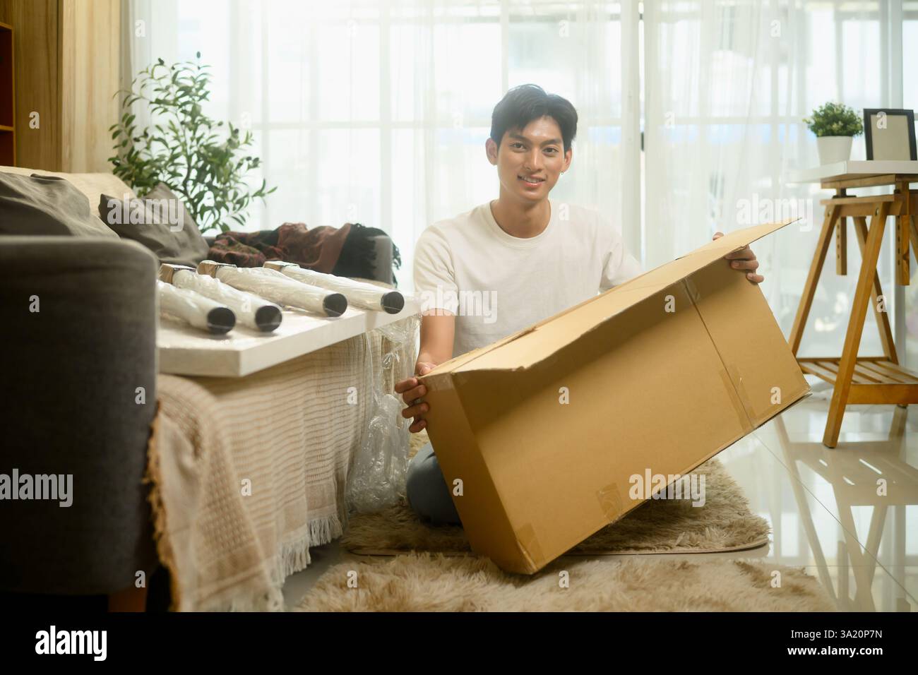 Young man unpacking parts of a new table from cardboard box preparing ...