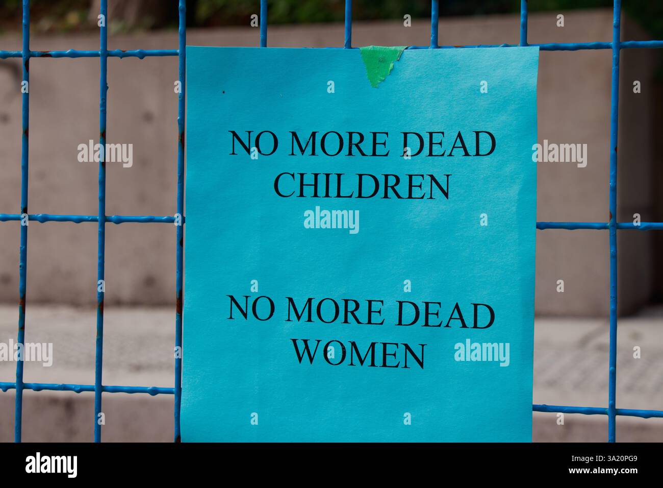 Blue paper sign on blue fence with bold black text reading "NO MORE ...