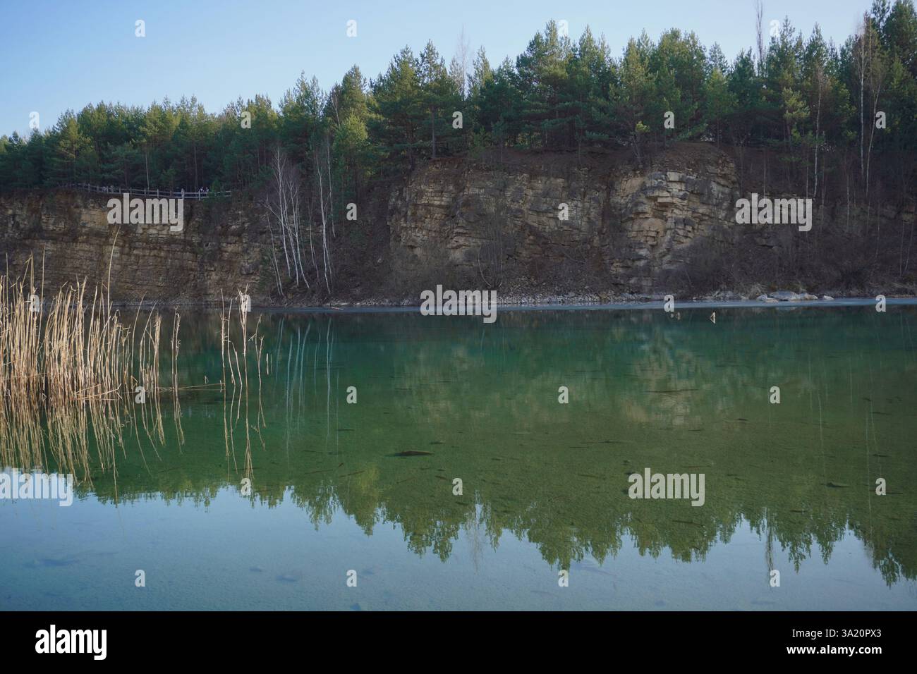 deep lake with green clean water in forest and rocks. mirroring trees ...