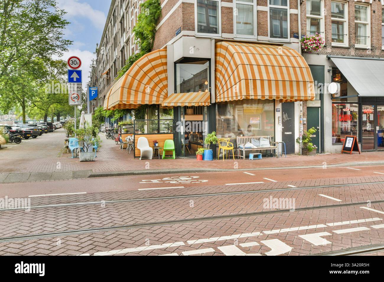 A vibrant street scene featuring outdoor cafes, parked bicycles, and ...