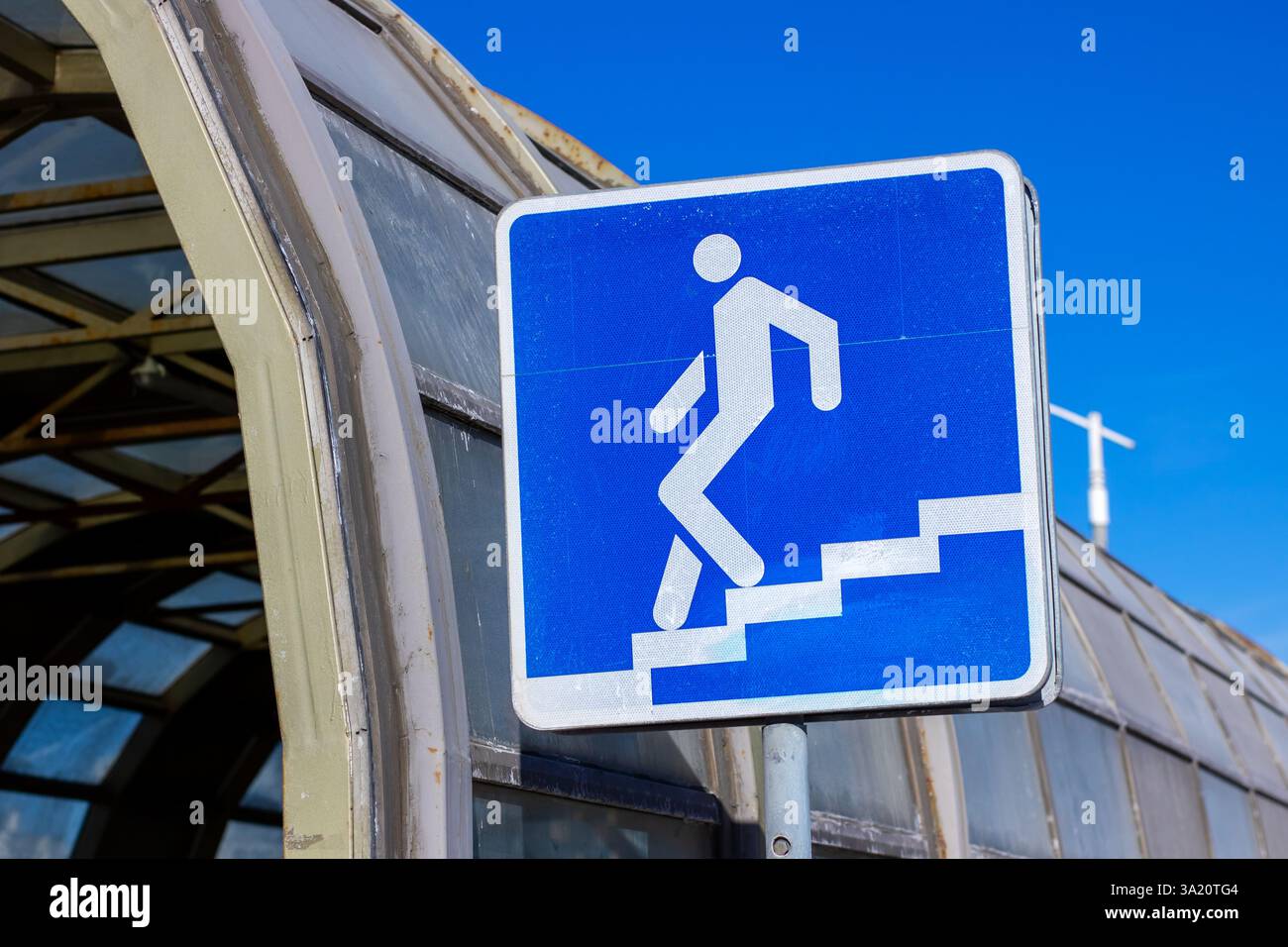 A vibrant blue sign displays an illustration of a man ascending a set ...