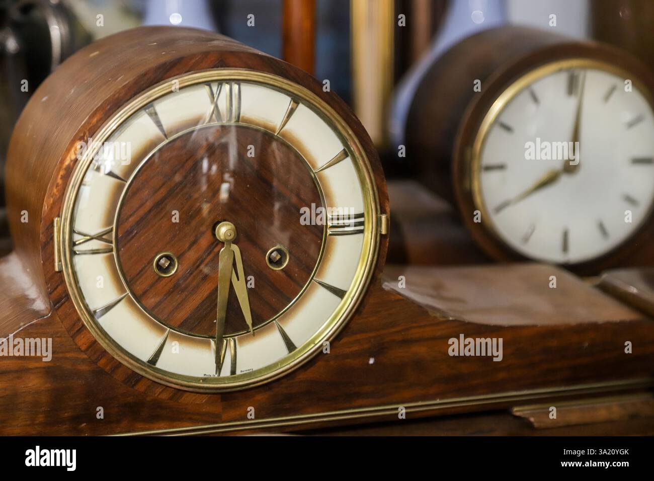 Two antique clocks sit on a wooden shelf, highlighting their unique ...