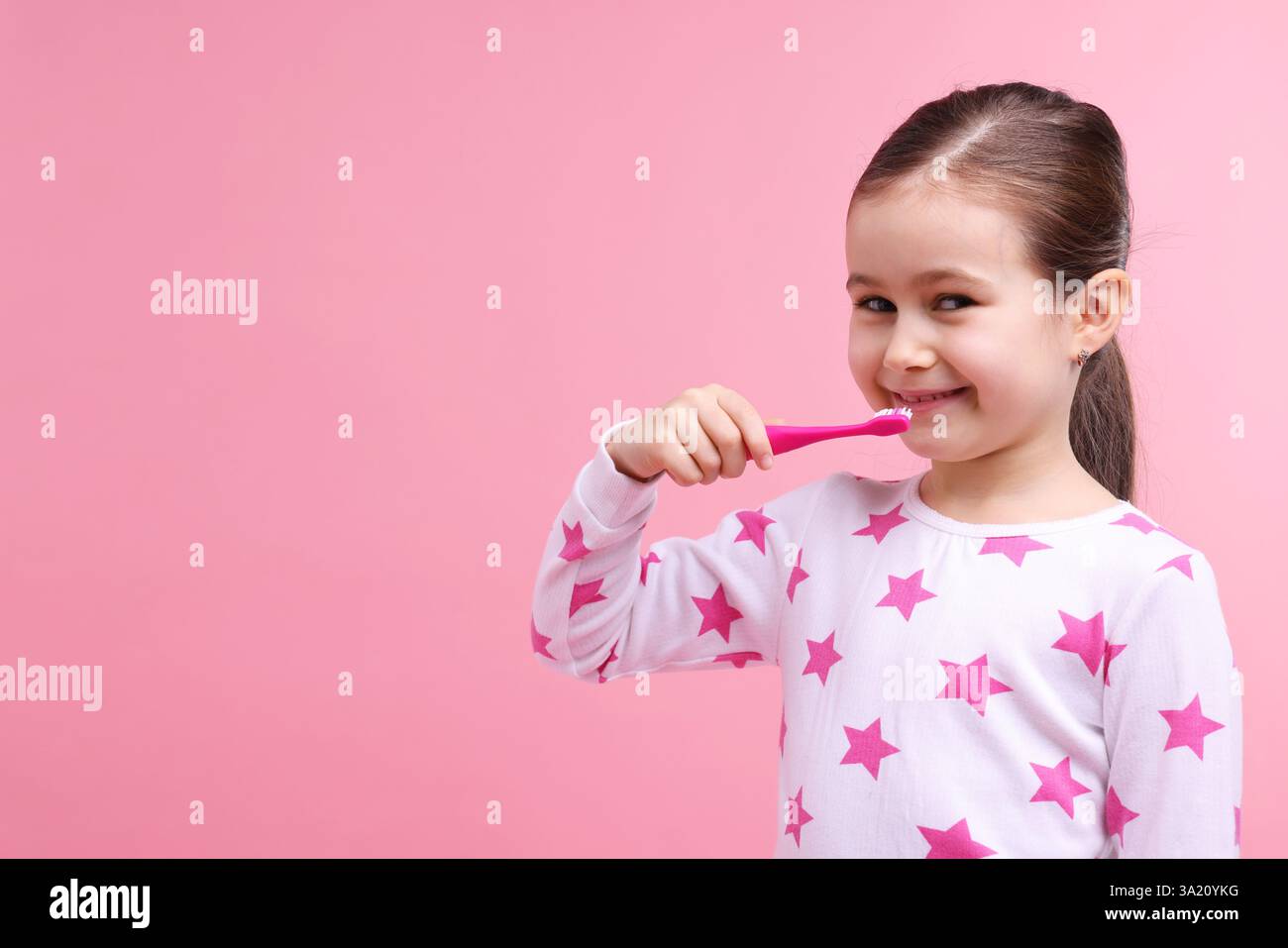 Cute girl brushing her teeth on pink background Stock Photo - Alamy
