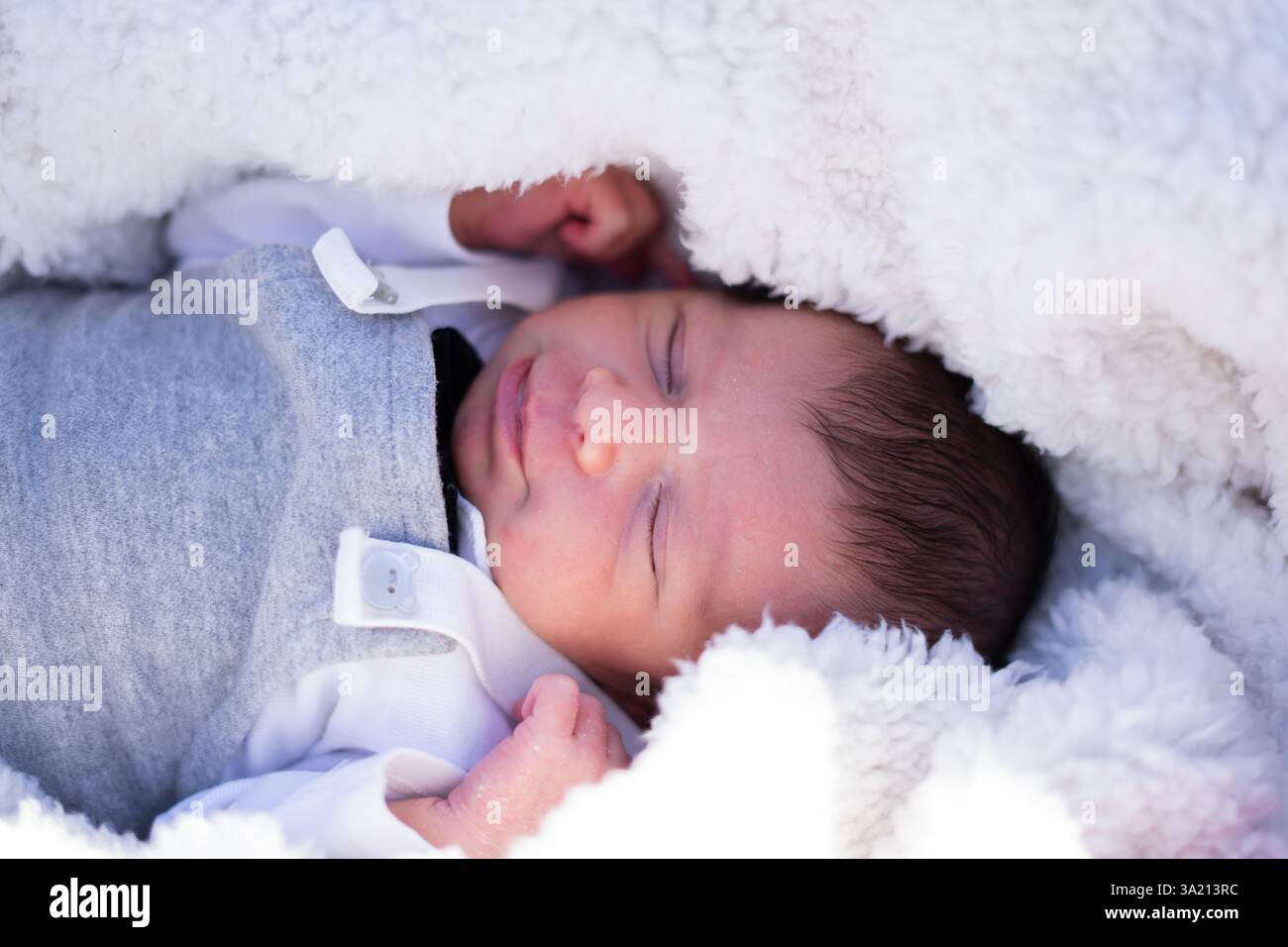 Newborn baby sleeping peacefully, wrapped in a soft white blanket ...