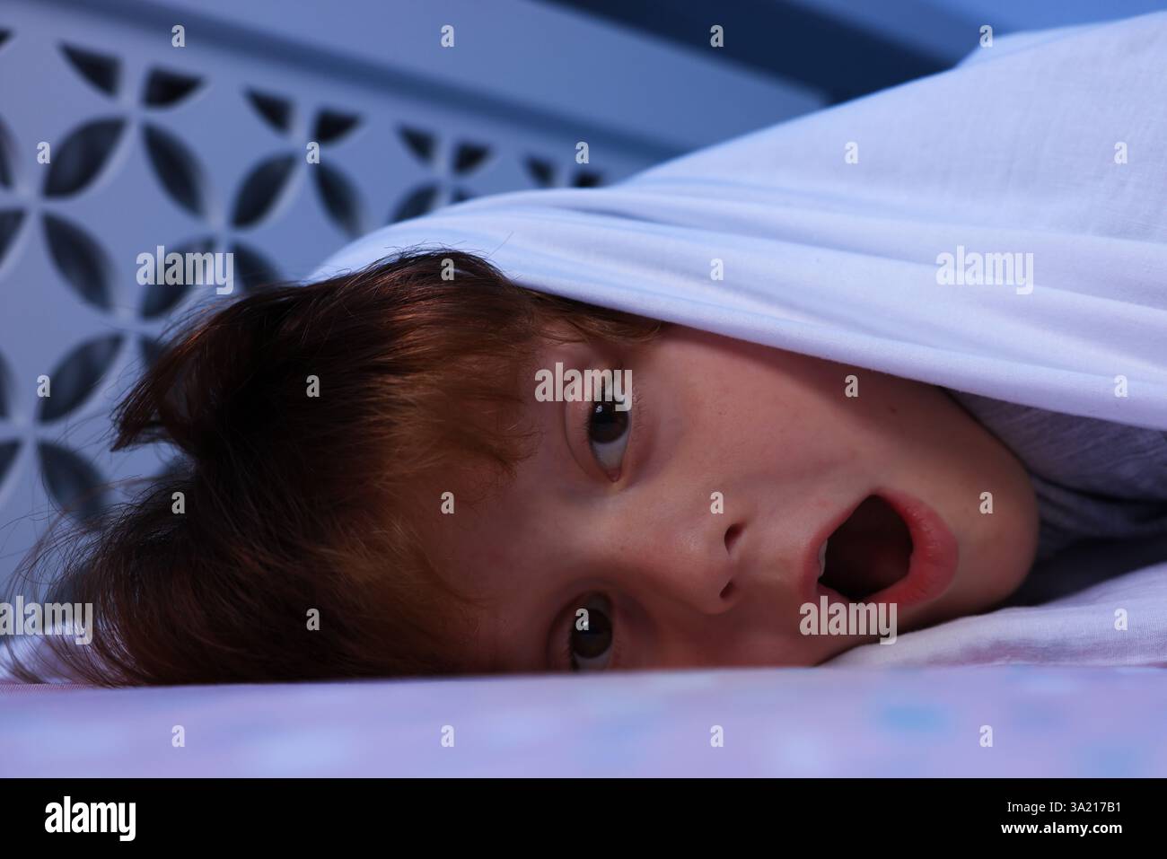 Afraid boy under blanket on bed at night Stock Photo - Alamy