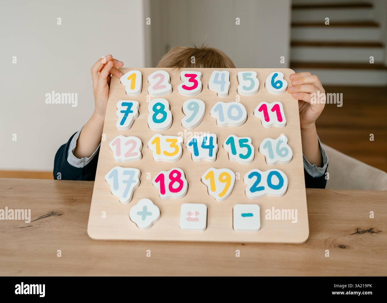 the boy learns to count, holds a board with numbers-puzzles arranged in ...