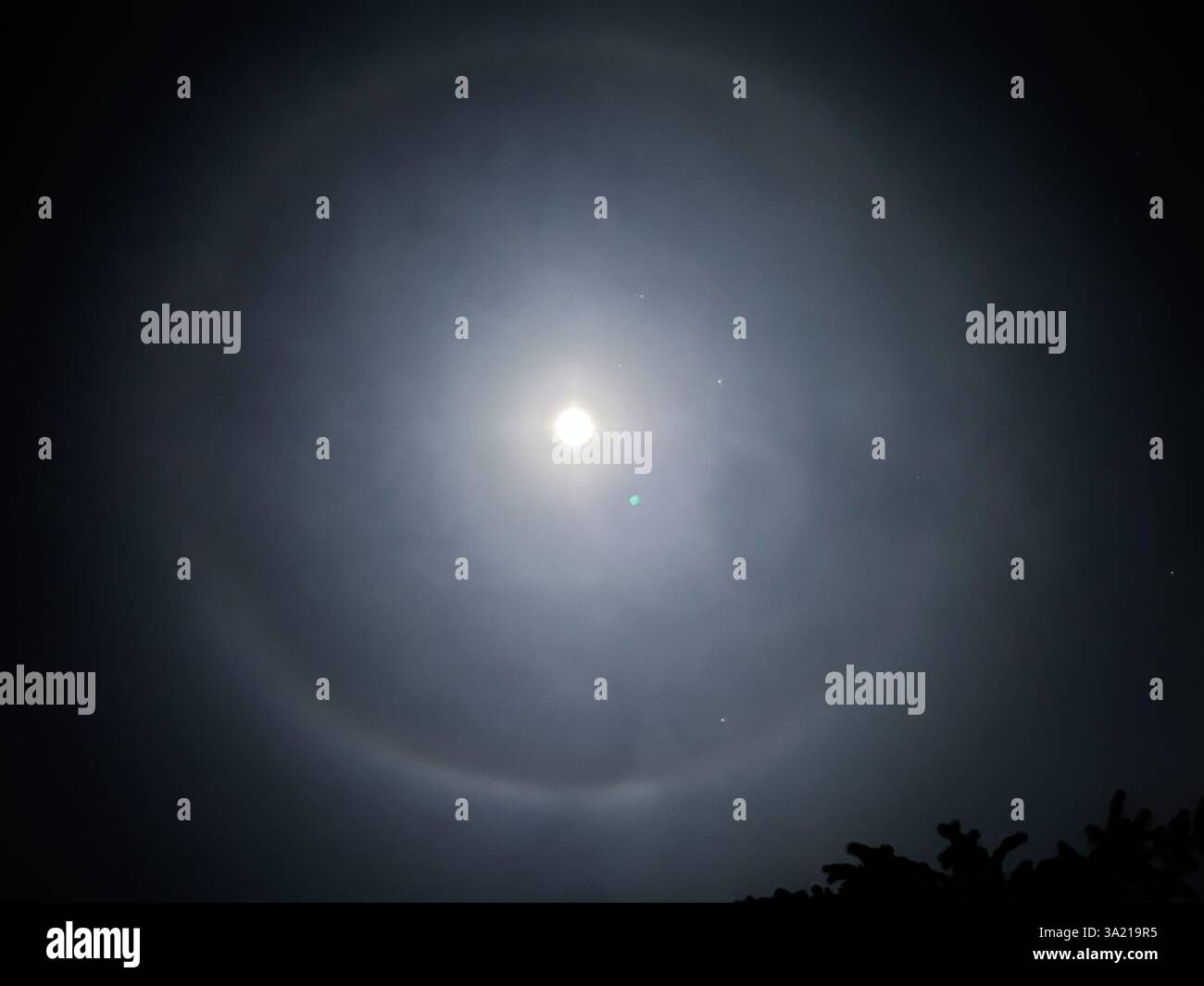 A radiant full moon encircled by a prominent halo in the clear night ...