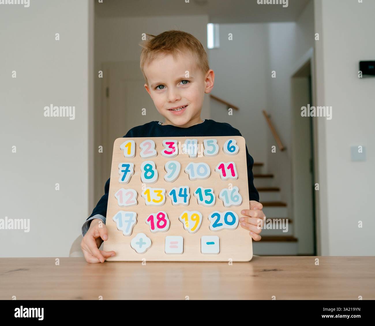 the boy learns to count, holds a board with numbers-puzzles arranged in ...