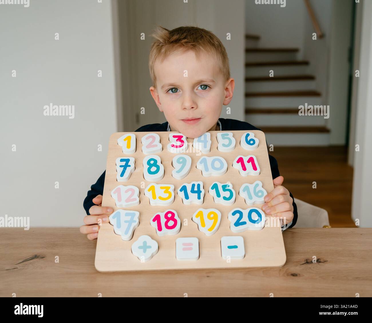 the boy learns to count, holds a board with numbers-puzzles arranged in ...