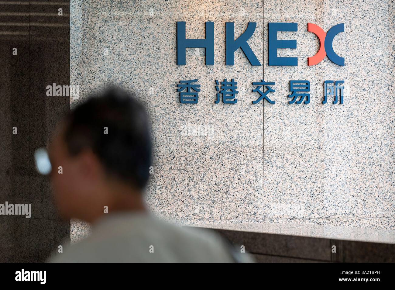 A man walks past the Stock Exchange of Hong Kong (HKEX) building and ...