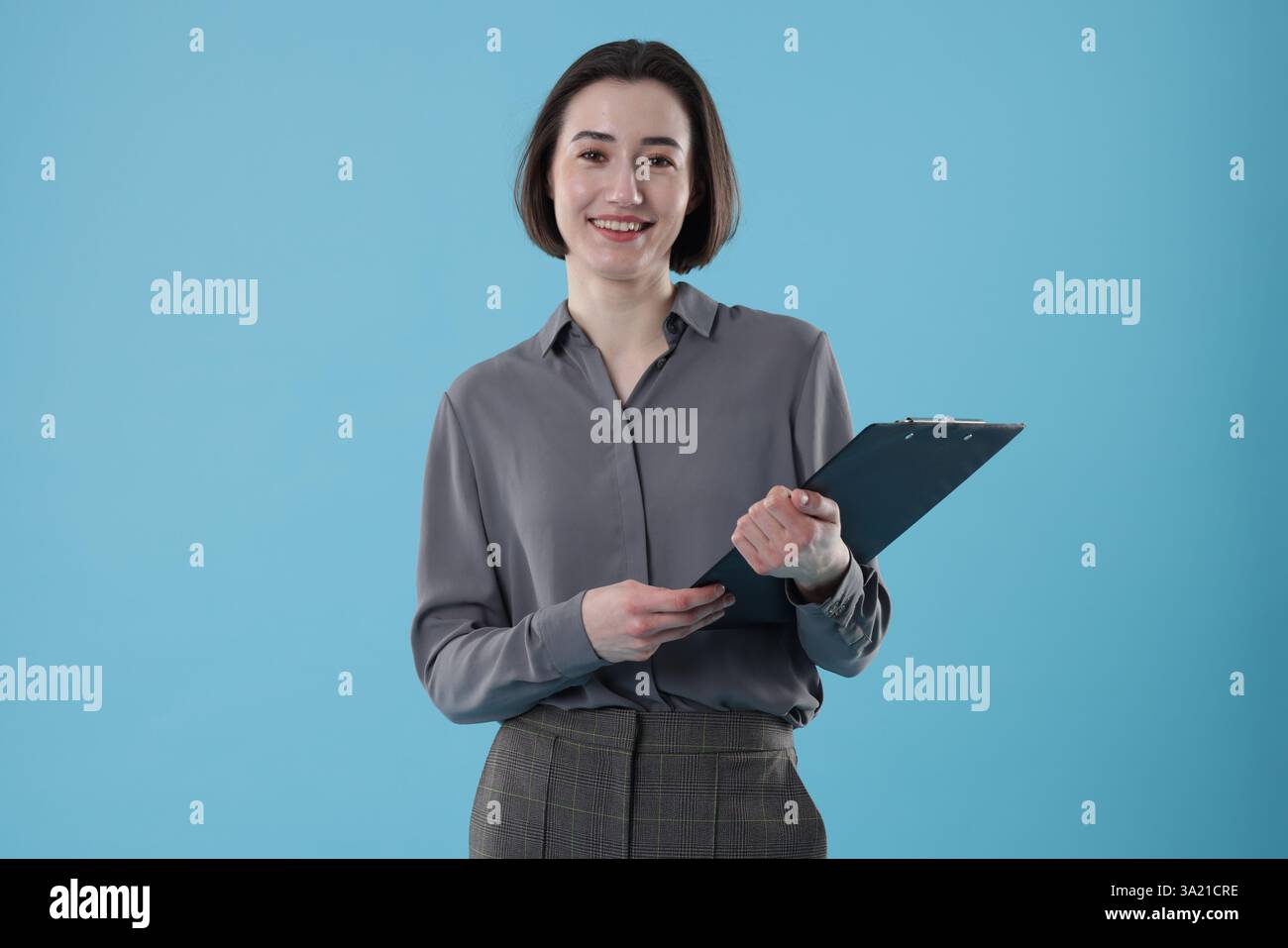 Portrait of young secretary with clipboard on light blue background ...